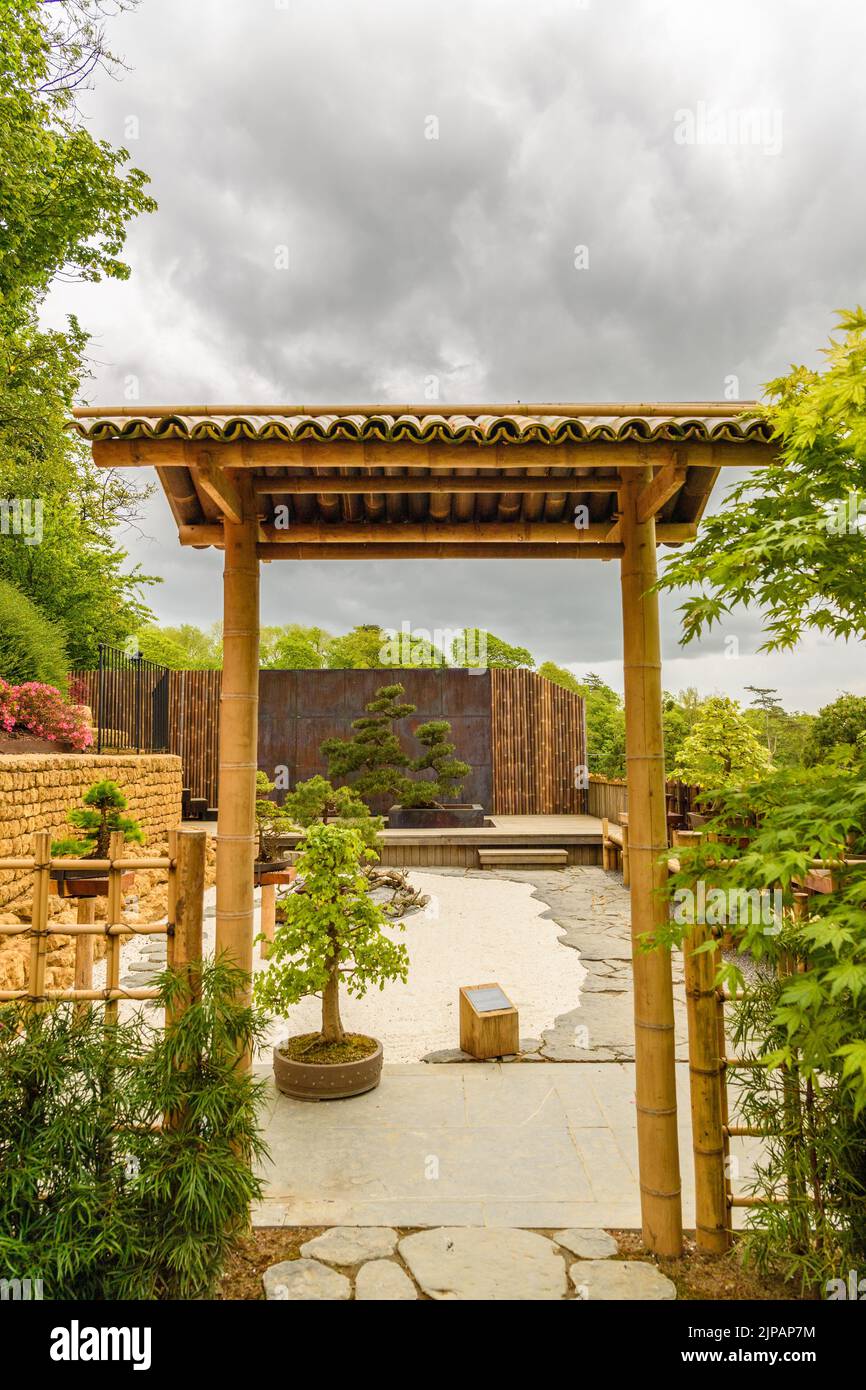 A vertical shot of an Asian-style fence leading to a yard with ...