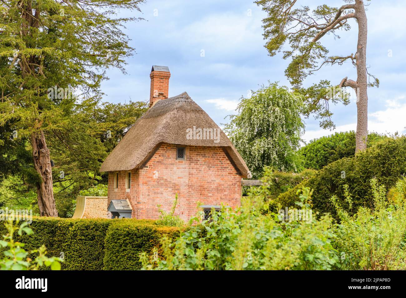 An atmospheric view of a red brick hut in the middle of beautiful trees ...
