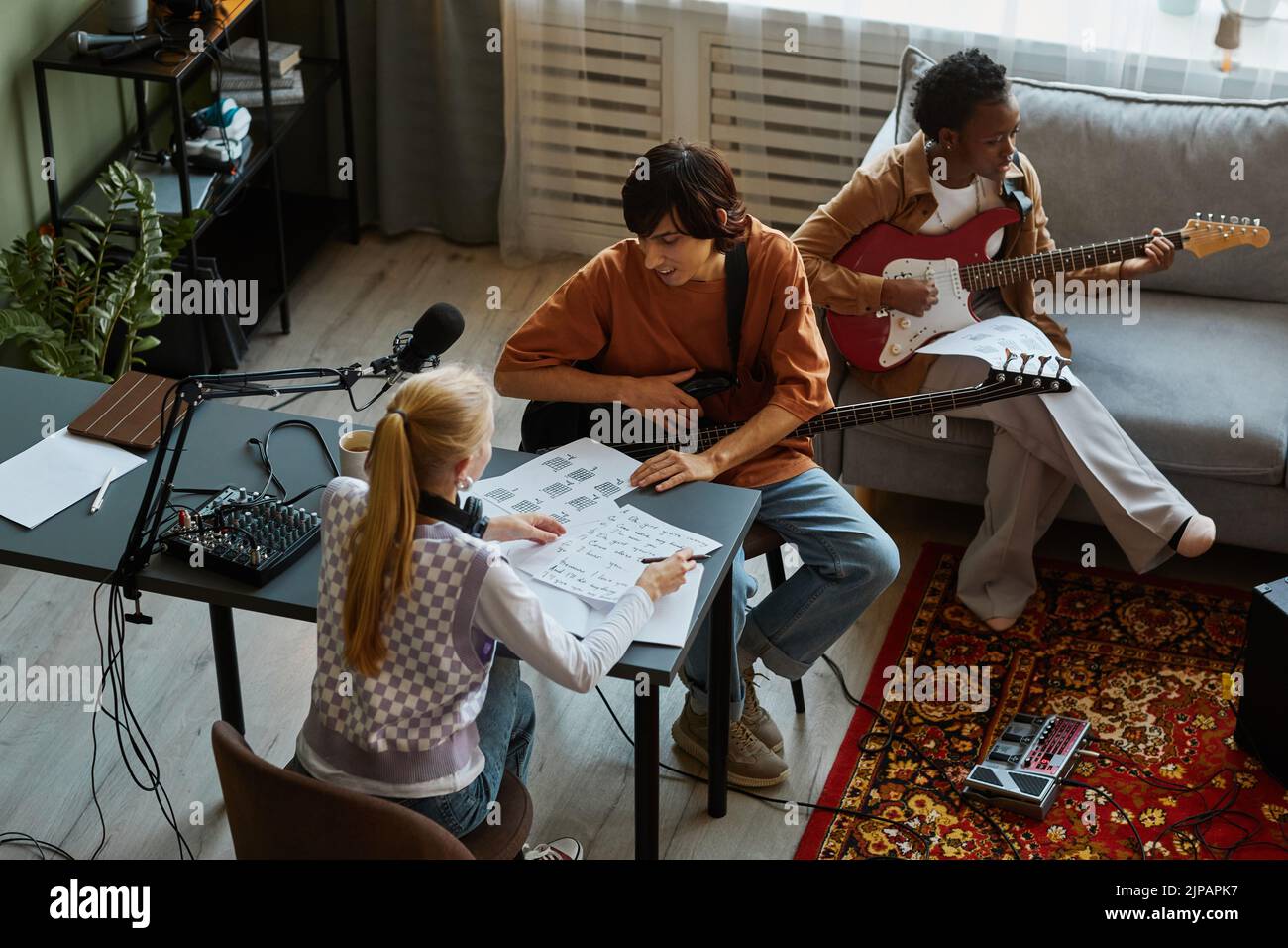 High angle view of young musicians writing songs together and playing ...