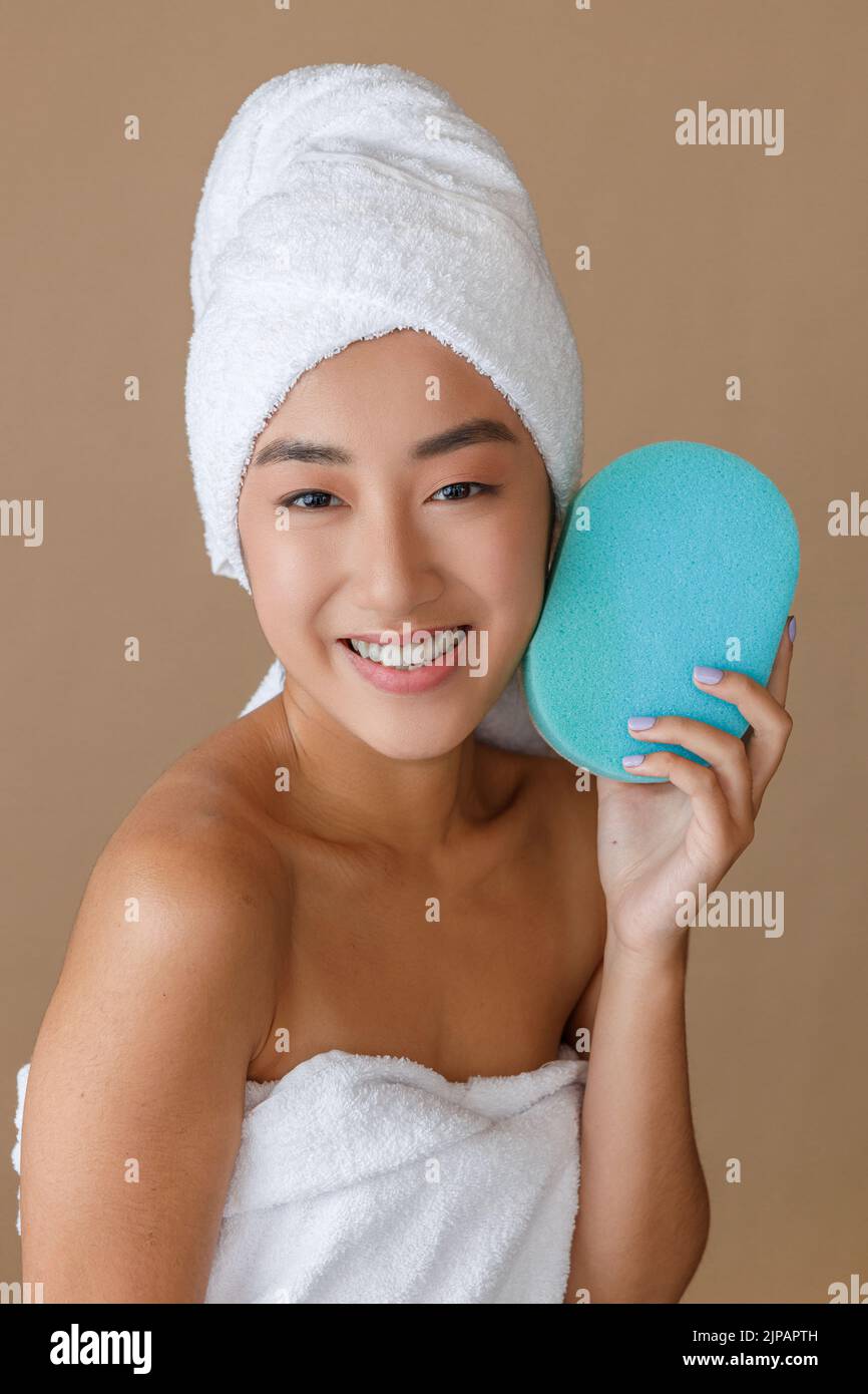 Cheerful Asian woman with shower sponge standing in studio Stock Photo ...