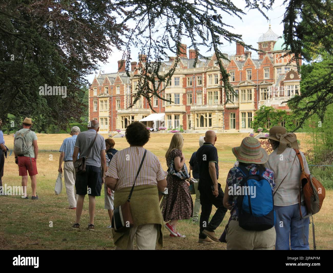 A group of visitors stand amongst the trees in the parkland at ...
