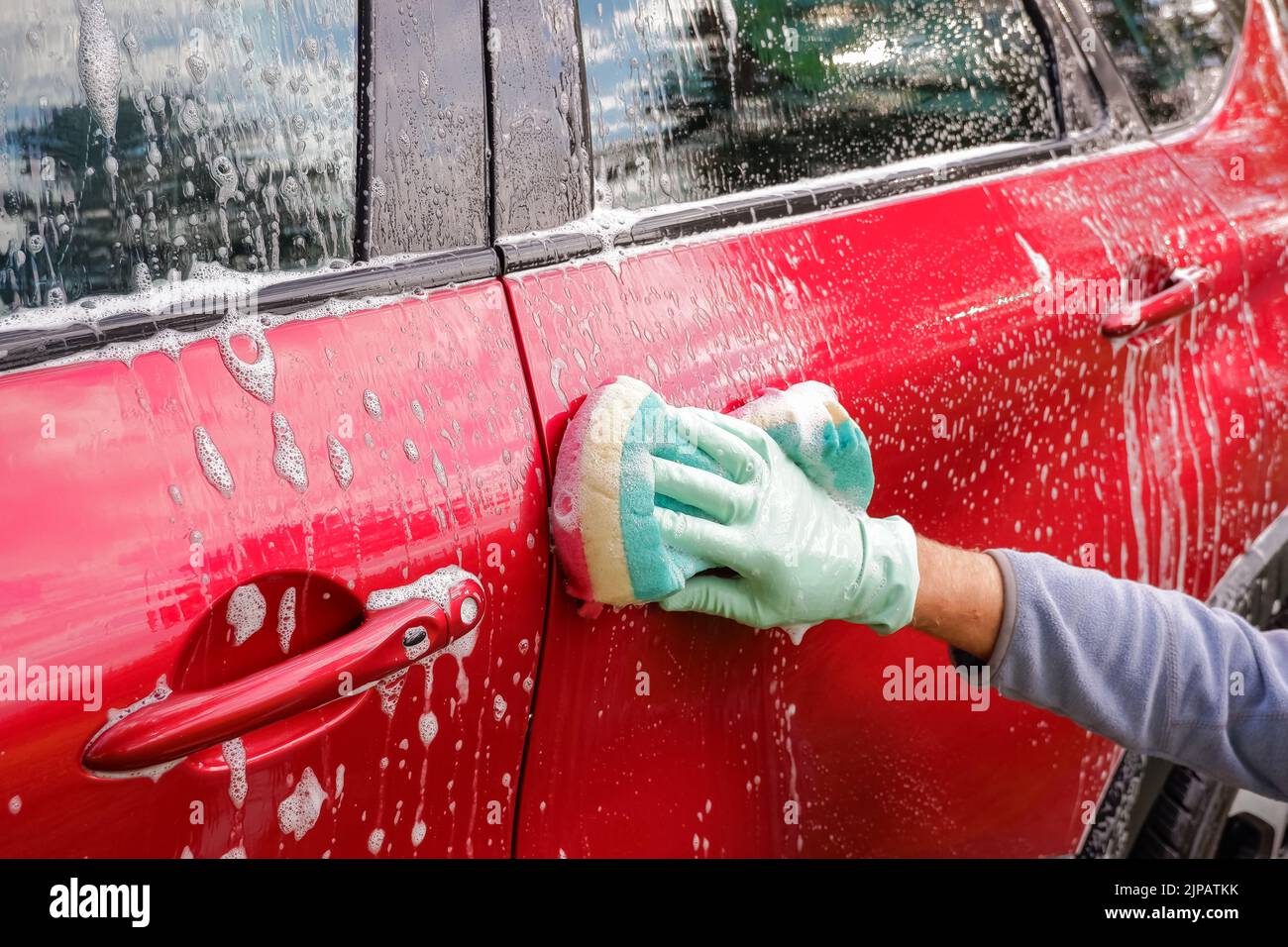 Worker washing red car with sponge on a car wash Stock Photo - Alamy