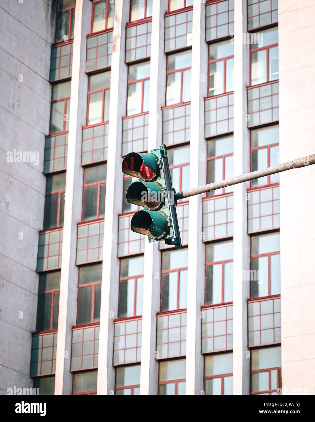 A vertical shot of a red traffic light against a modern building in ...