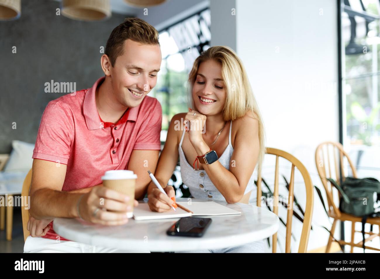 Happy students sitting in cafe table of university and doing homework ...