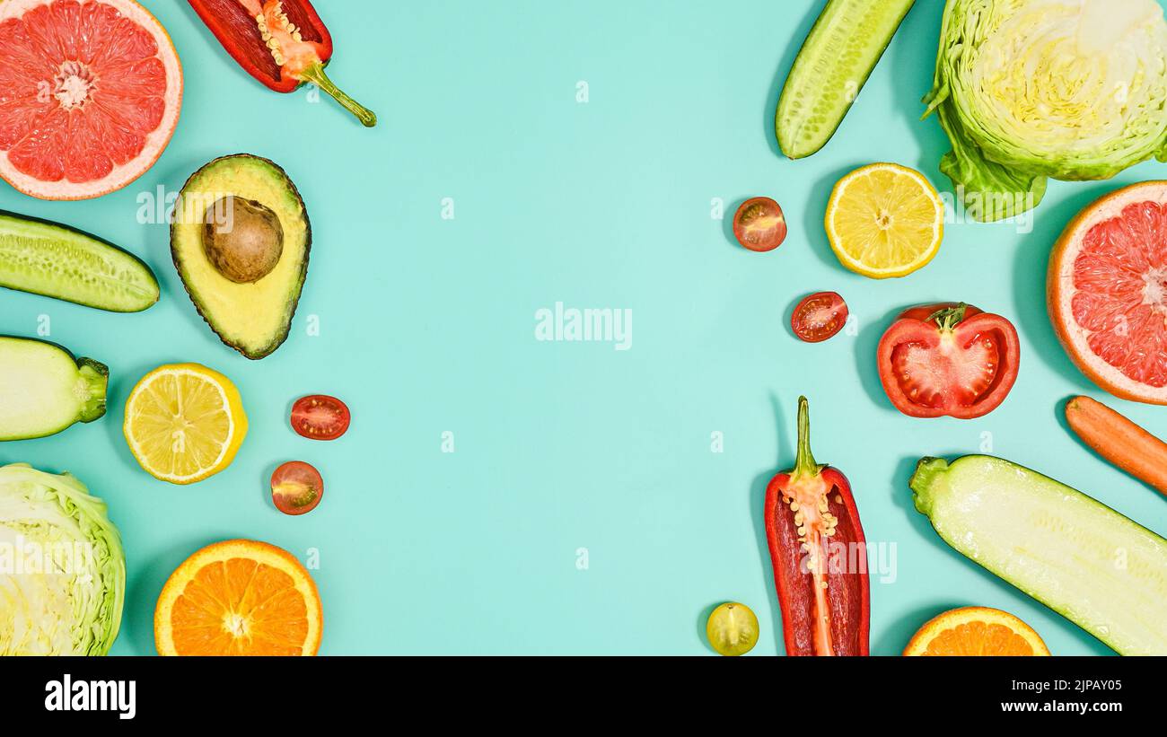 Copy space background with sliced fresh fruits and vegetables on cyan ...