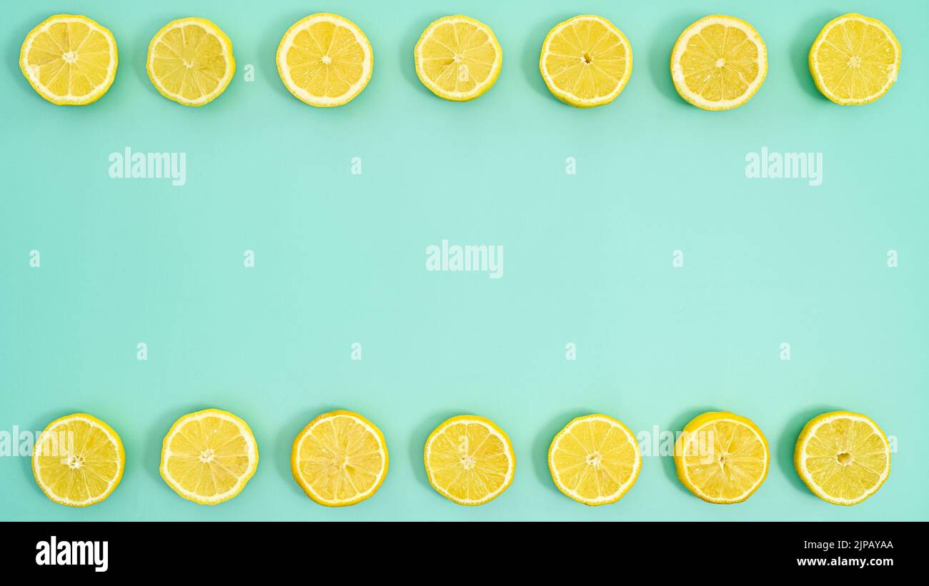 Half sliced lemons on top and bottom of cyan background. Flat lay ...