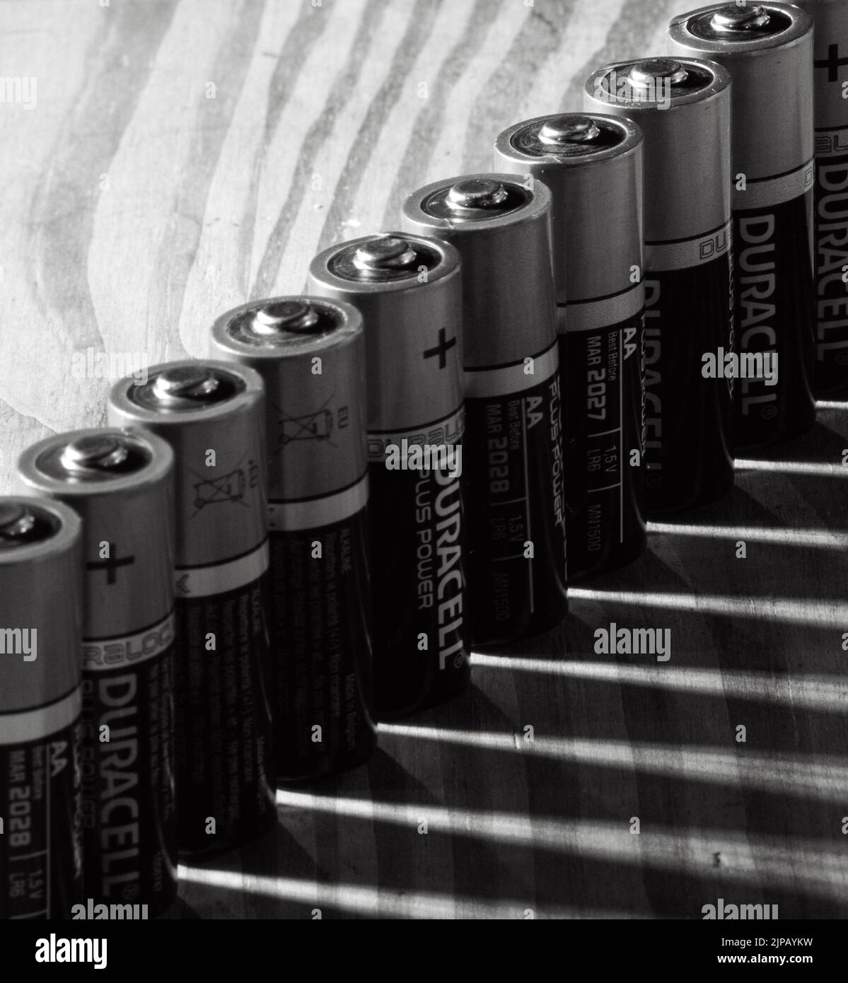 A closeup of batteries all in a line casting a shadow Stock Photo - Alamy
