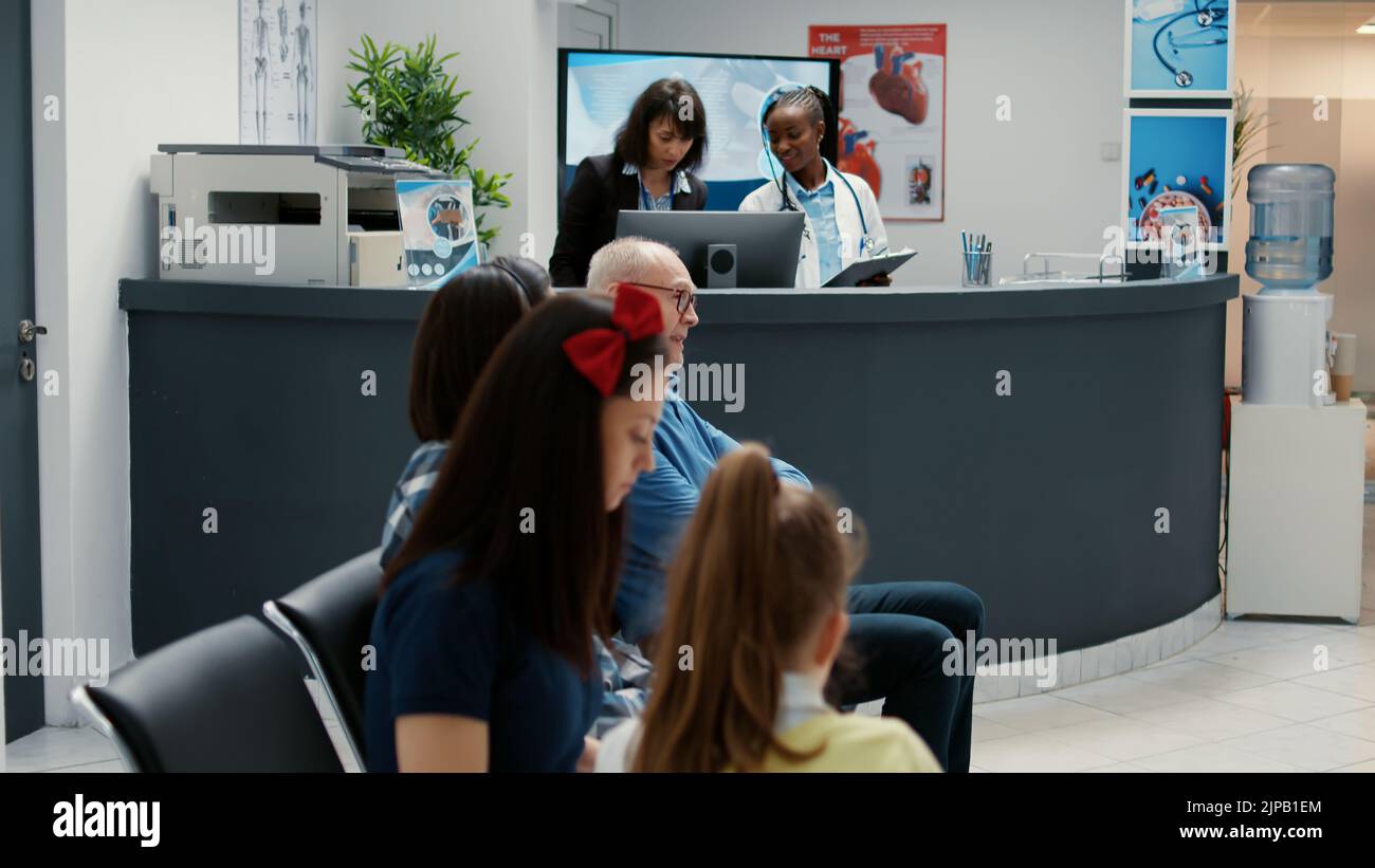 Many diverse people waiting to write medical report at reception desk ...