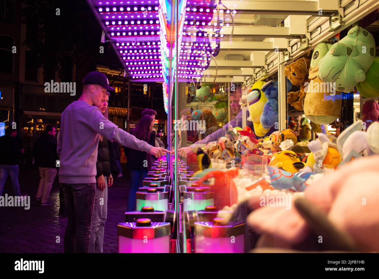 A young couple looking at the prices in front of claw machines in a ...