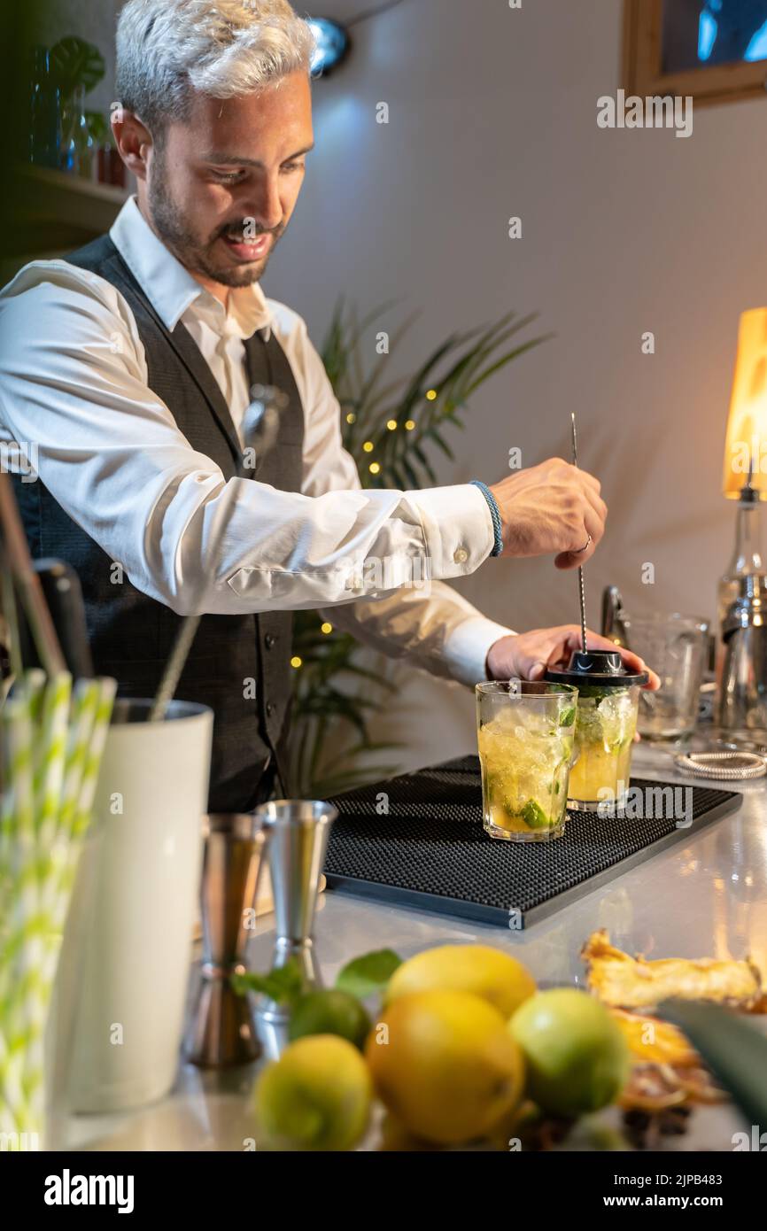 Barman making cocktail Mojito in night club adding ingredients and ...