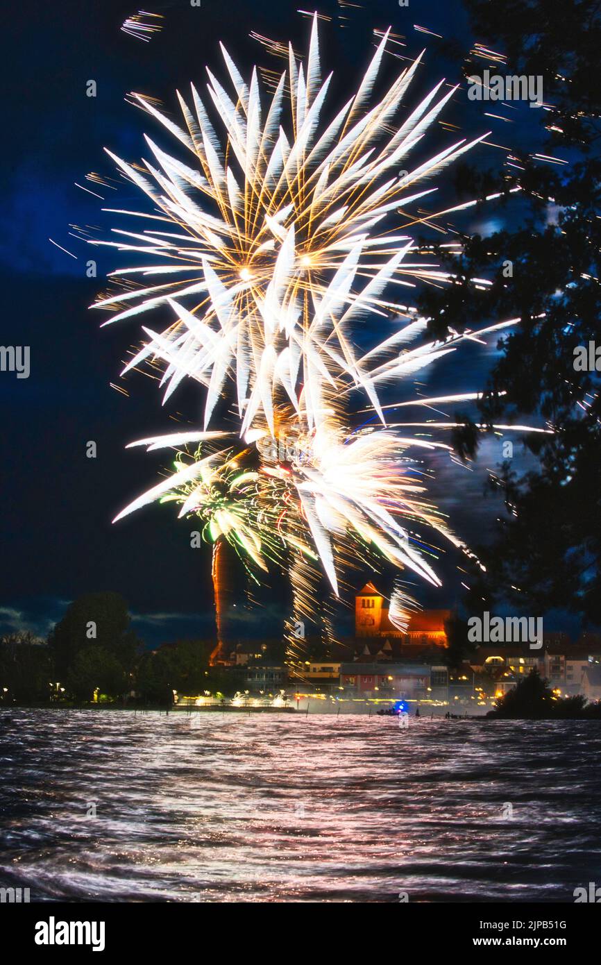 A long-exposure shot of bright fireworks in the sky set up from a dock ...