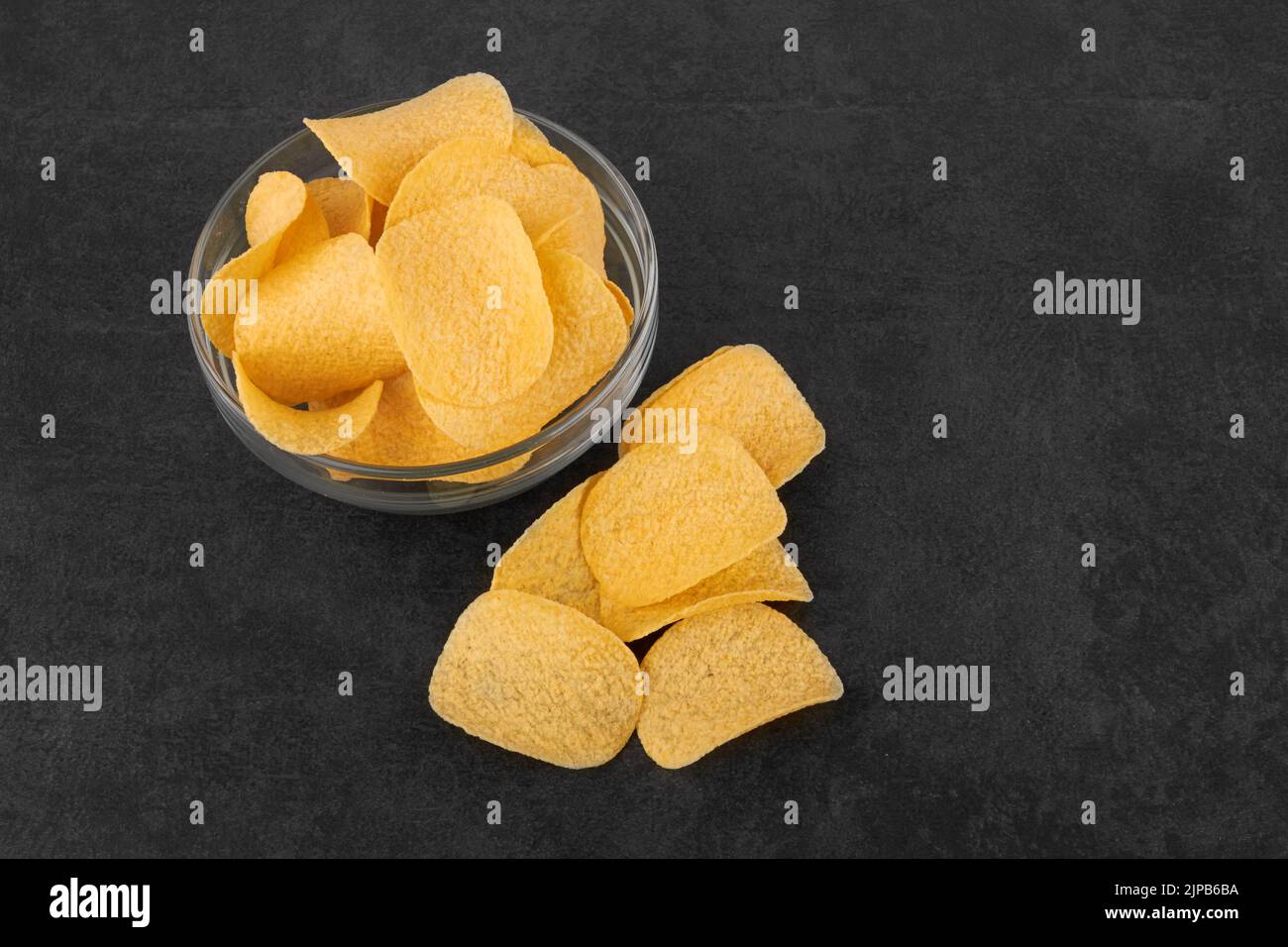 Potato chips on a stone black surface in a saucer Stock Photo - Alamy