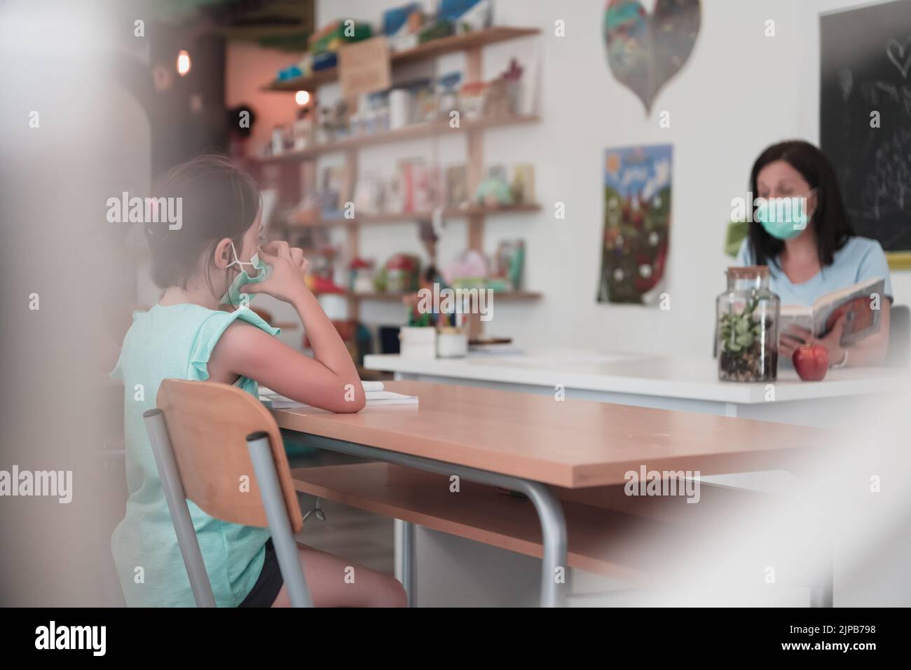Multiracial group of kids wearing face masks working at class, writing ...