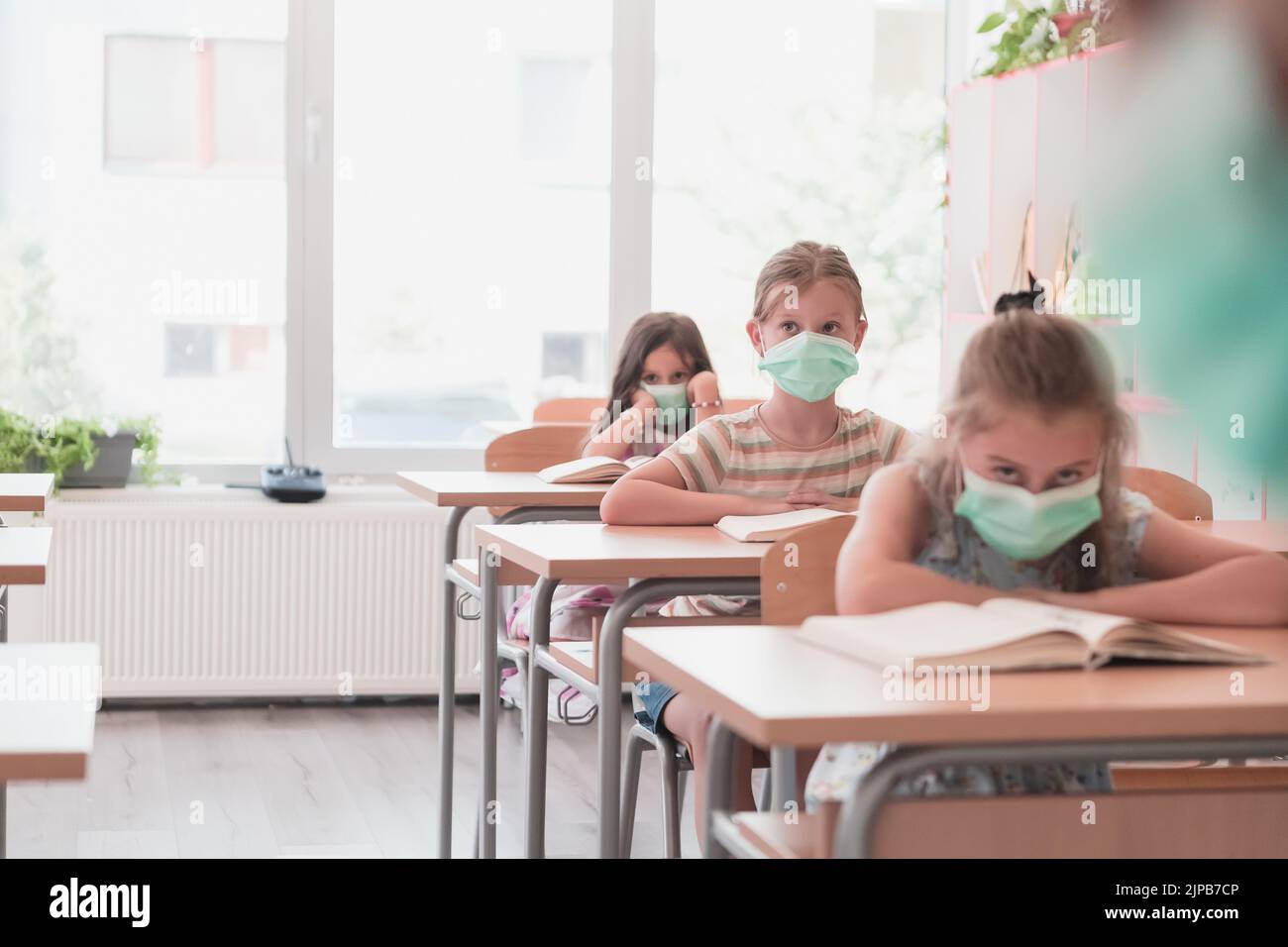 Multiracial group of kids wearing face masks working at class, writing ...