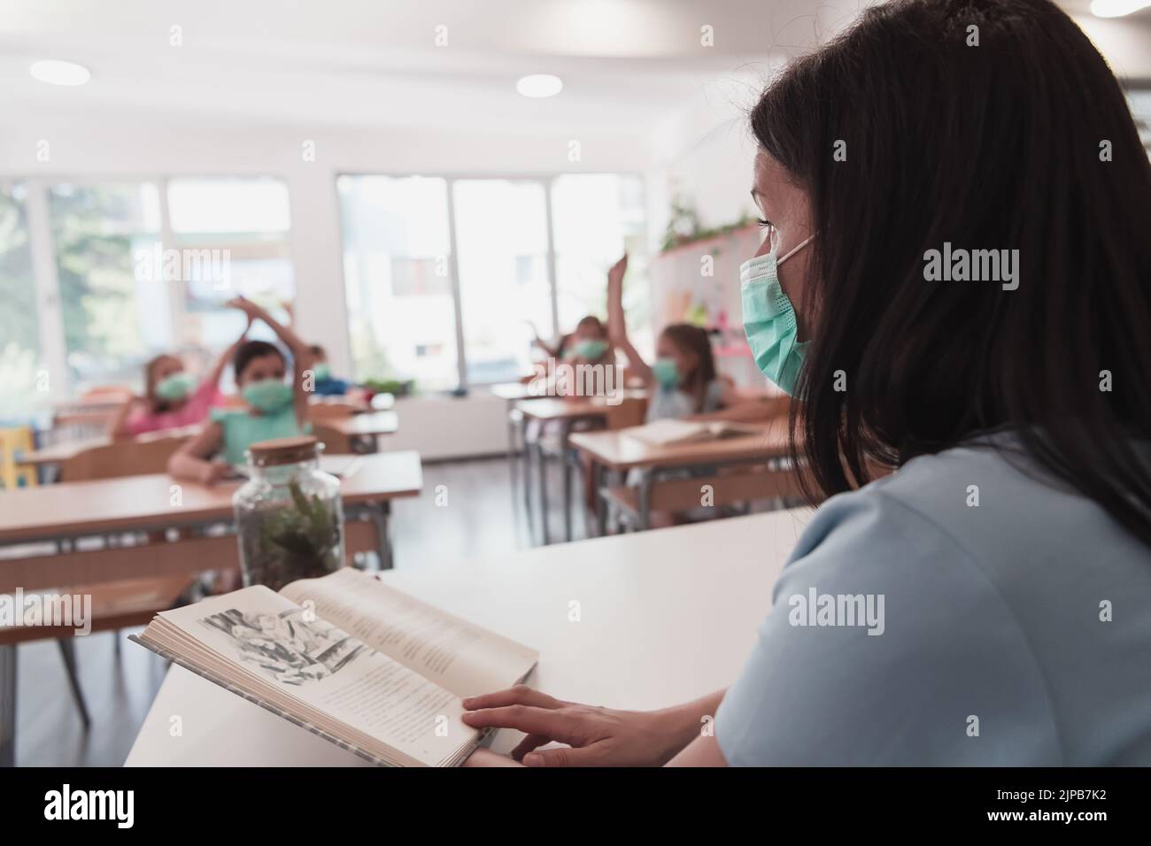 Multiracial group of kids wearing face masks working at class, writing ...