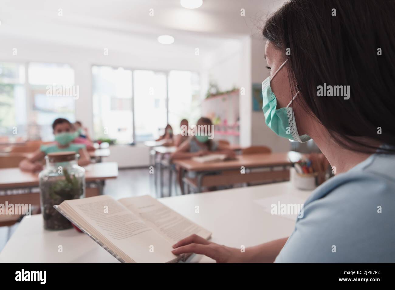 Multiracial group of kids wearing face masks working at class, writing ...