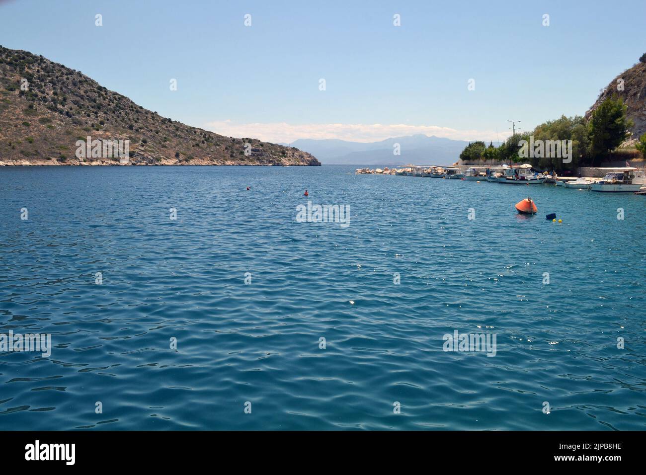 Fishing boats and Romvi island in Tolo Village Stock Photo - Alamy
