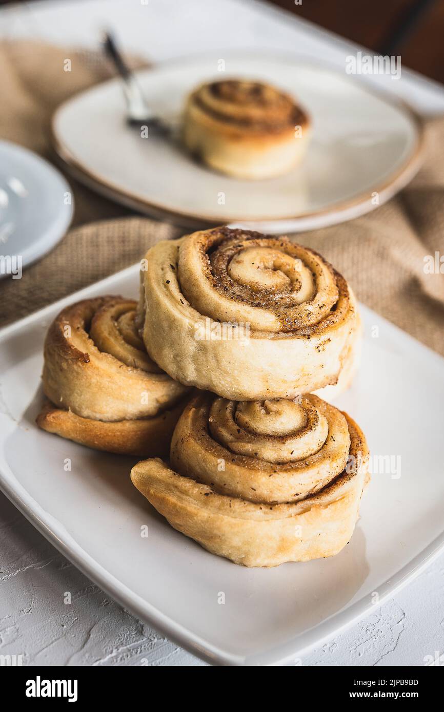 A vertical shot of three cinnamon rolls stacked on top of each other on ...