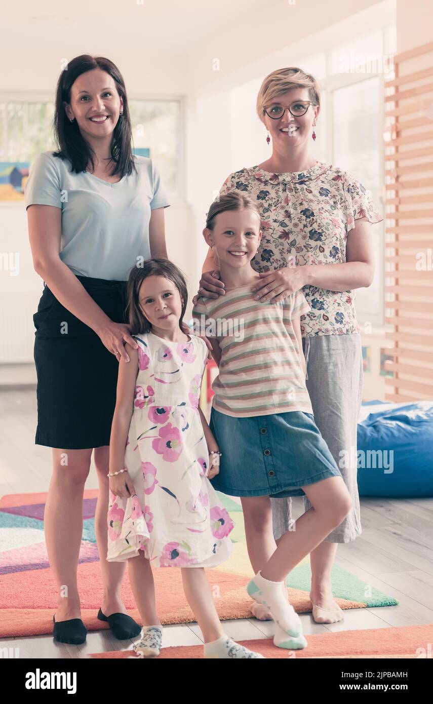Portrait of a mother with her daughters in a modern preschool ...