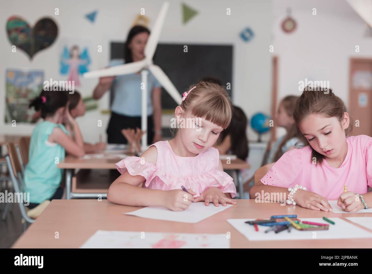 Little girls sitting in elementary school drawing on paper with their ...
