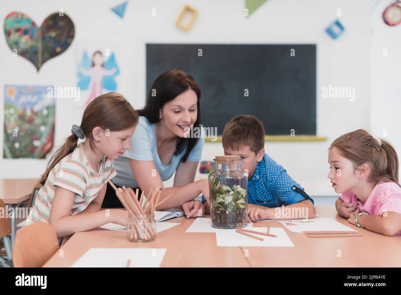 Female Teacher with kids in biology class at elementary school conducting biology or botanical ...