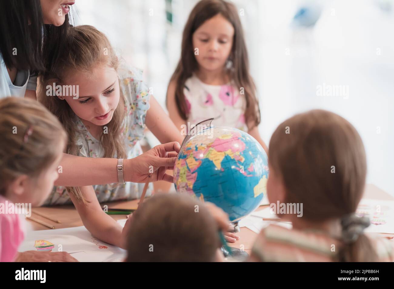 Female teacher with kids in geography class looking at globe. Side view ...