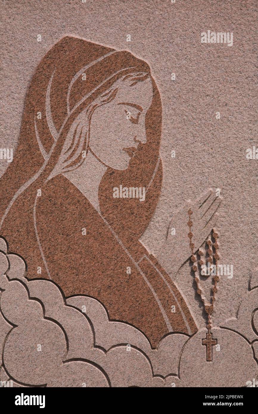 Religious figure in prayer depicted on memorial monument in cemetery ...
