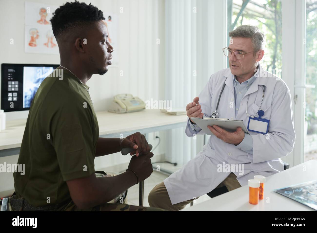 General practitioner asking questions military man and filling form on ...