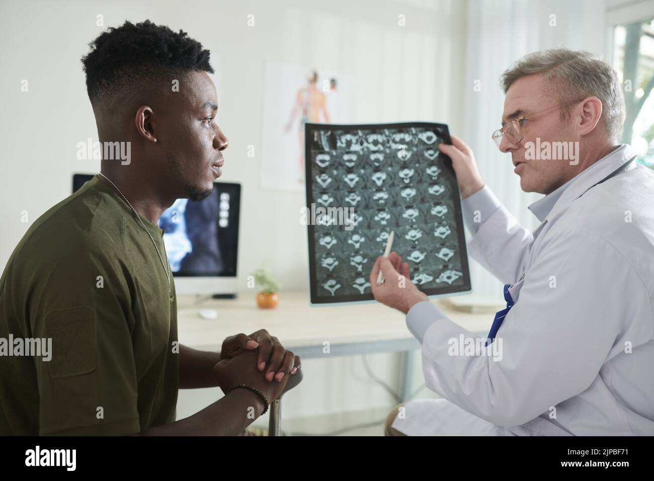 Doctor pointing at spine discs MRI image when explaining cause of back ...