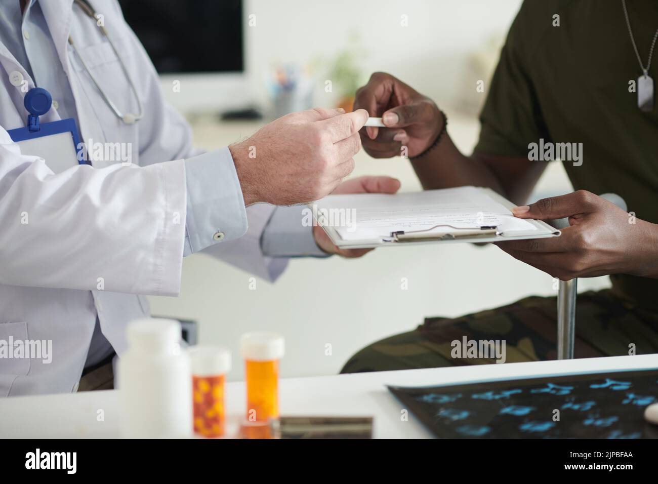 Doctor giving pen and medical form to military man to fill before ...