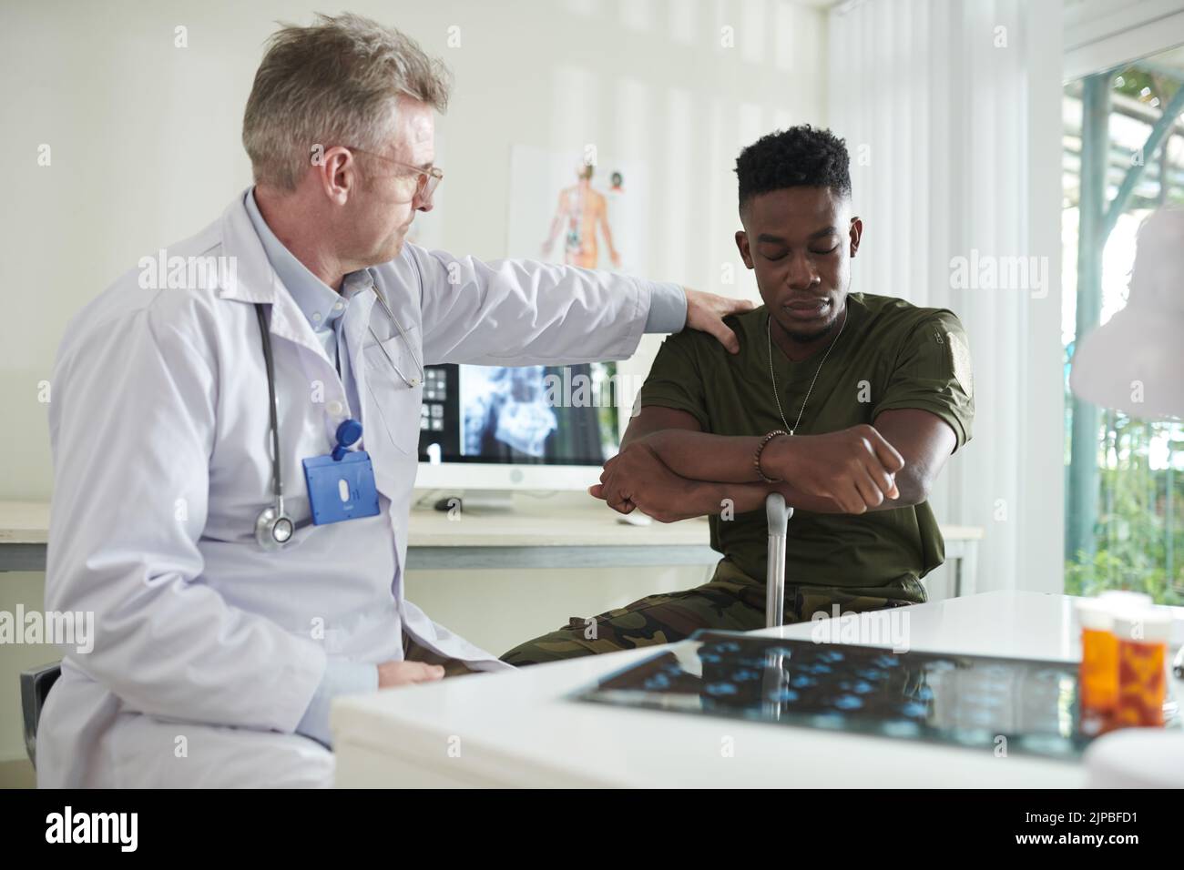 Doctor touching shoulder of Black military man suffering from severe ...