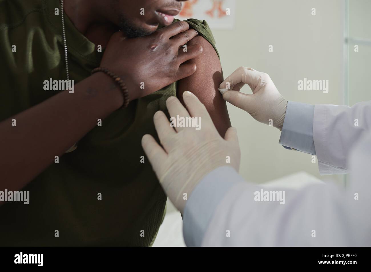 Military doctor using cotton swab moistened with alcohol to wipe arm of ...