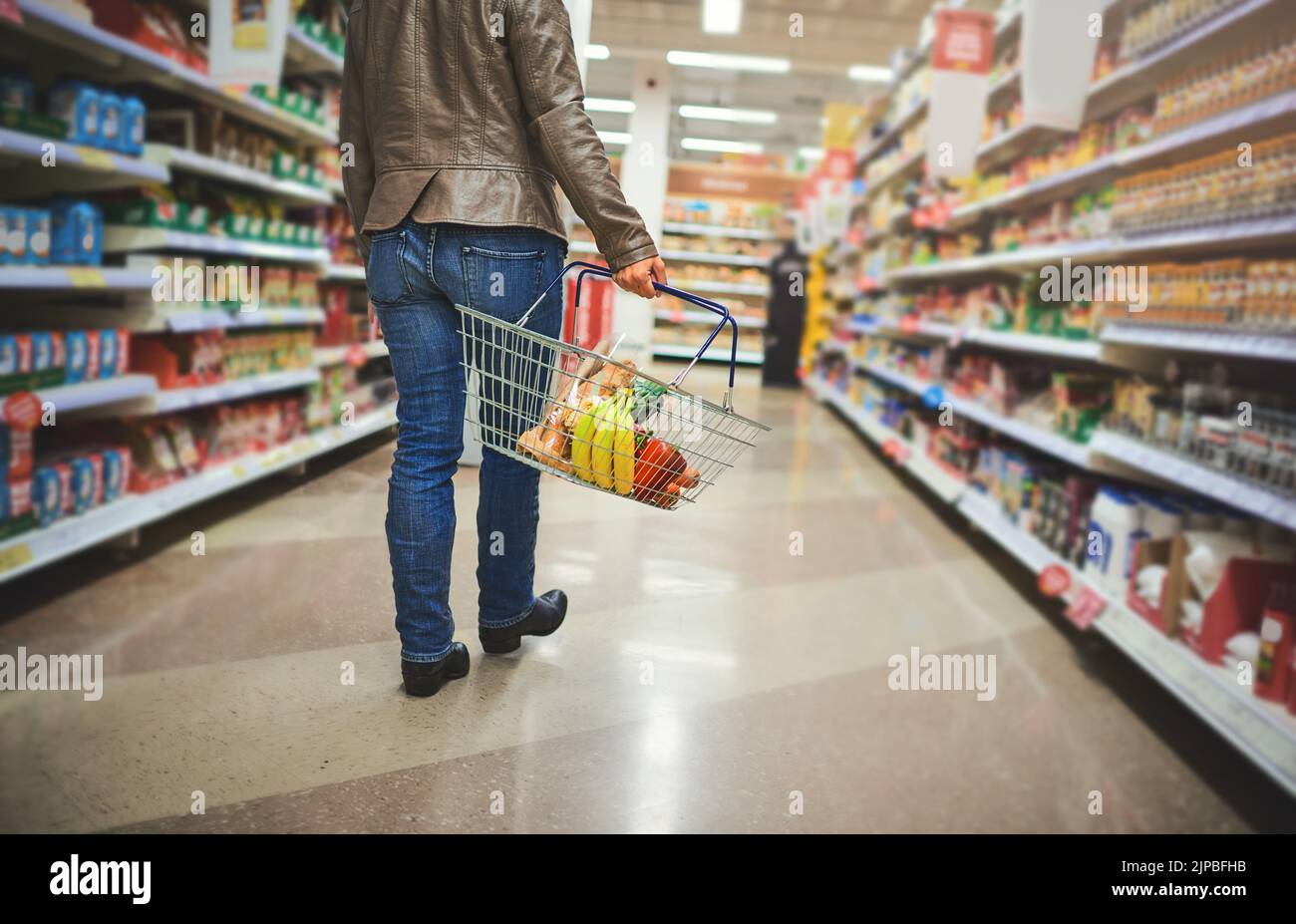 Stocking up on staples. a woman holding a basket while shopping at a ...