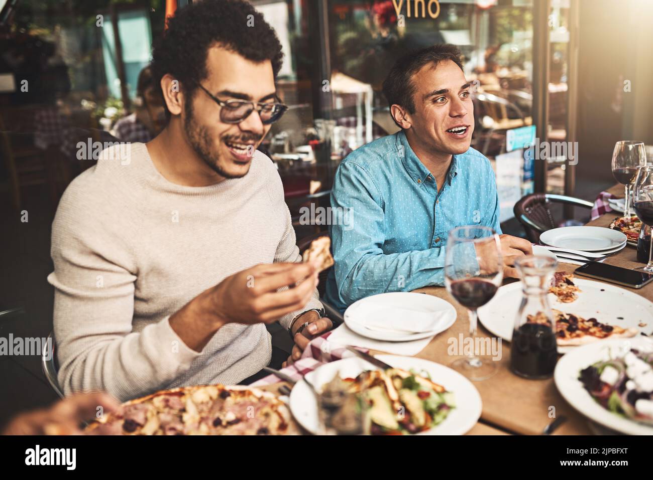 Where shall I start. two cheerful young men seated at a table eating ...