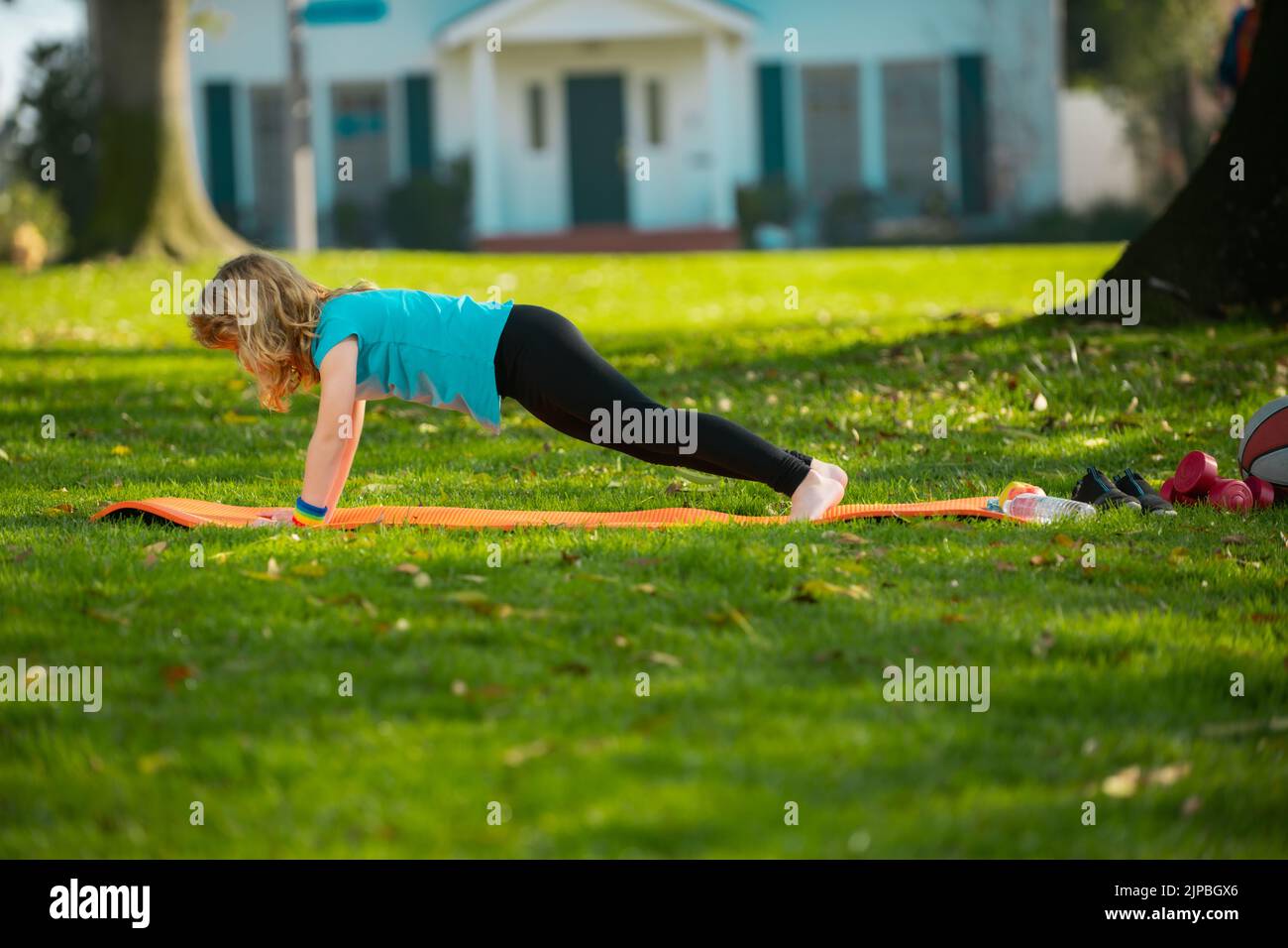 Sport kids. Child is pushing up on the green grass. Boy doing push-ups ...