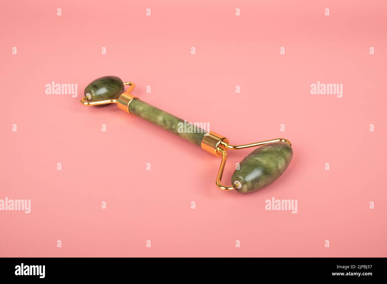 jade stone for face skin care on pink background Stock Photo - Alamy