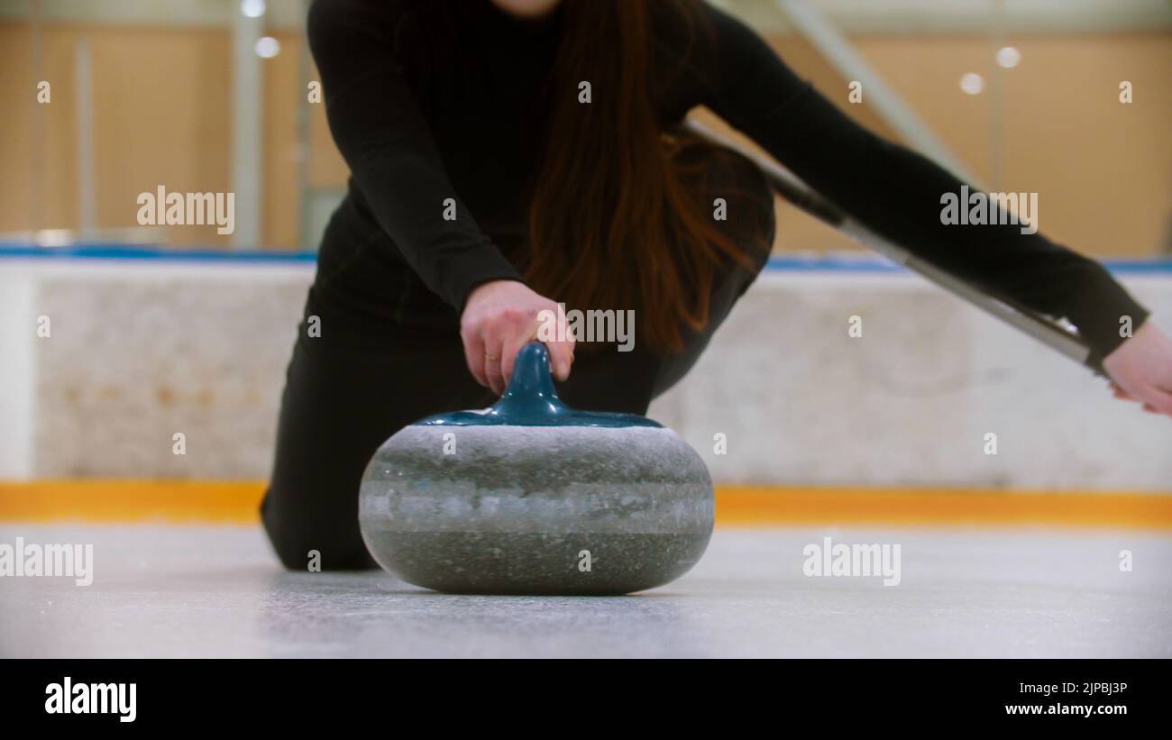 Curling - holding a granite stone with blue handle on the ice field ...