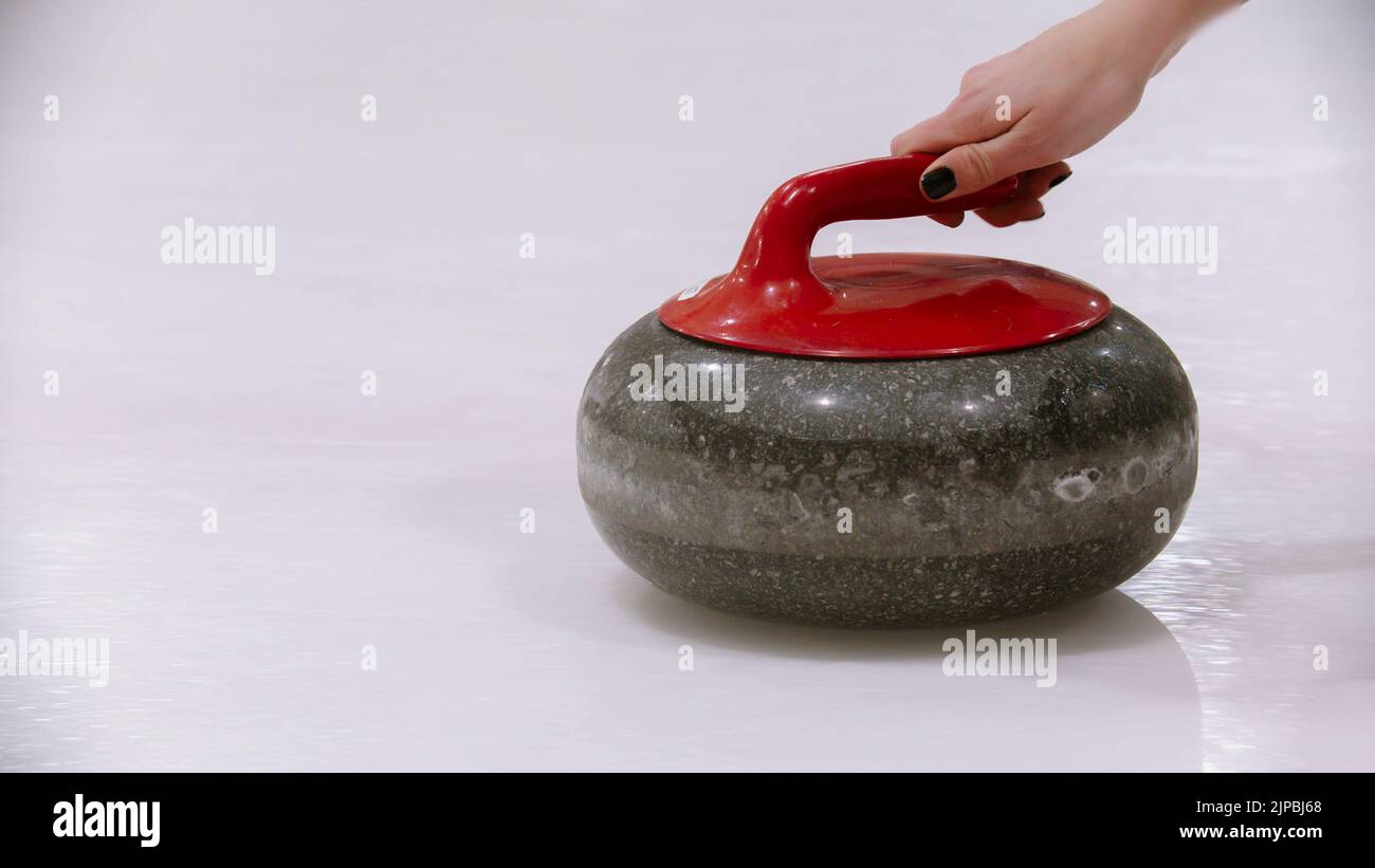 Curling training - woman holding a granite stone with red handle Stock ...