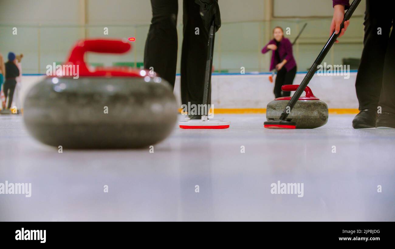 Curling training on the ice rink- a granite stone biter with red handle ...