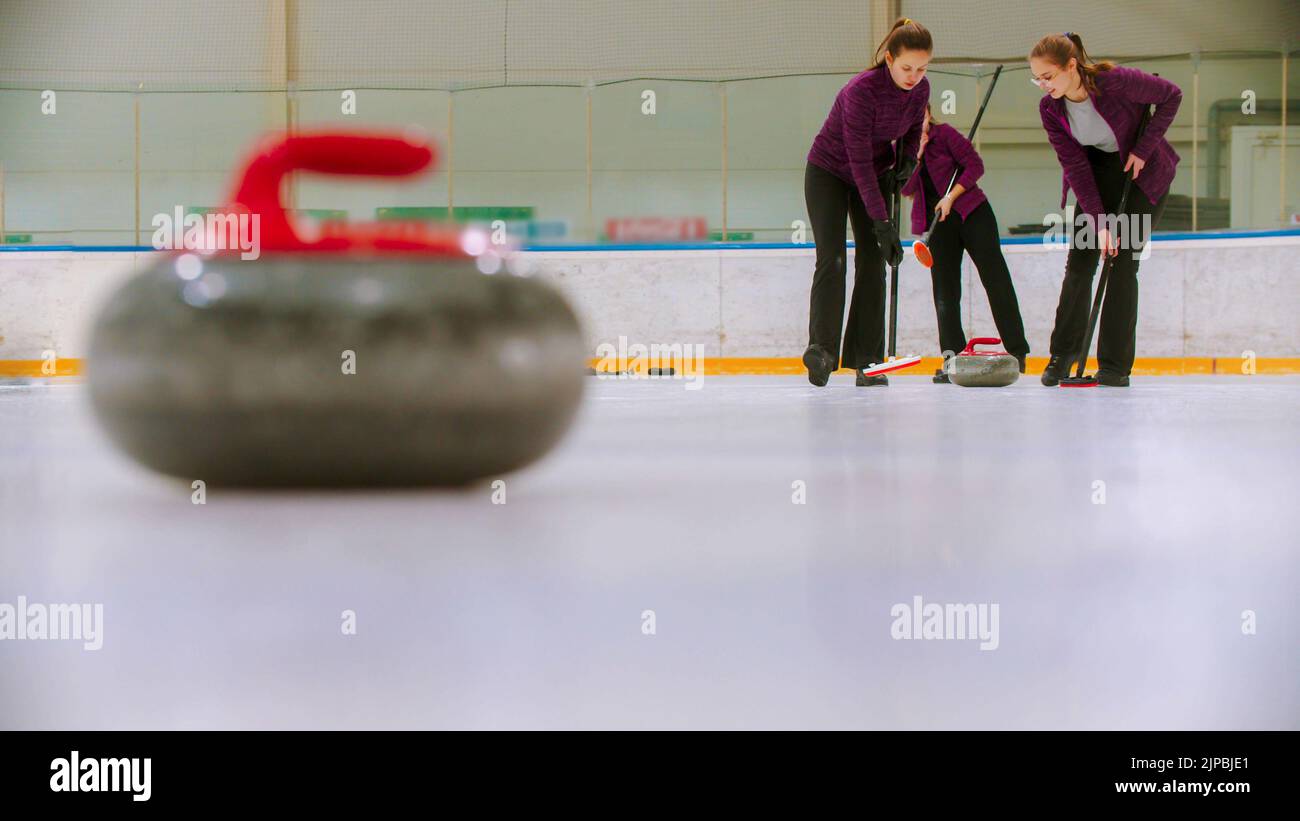 Curling training - leading granite stone on the ice - two women rubbing ...