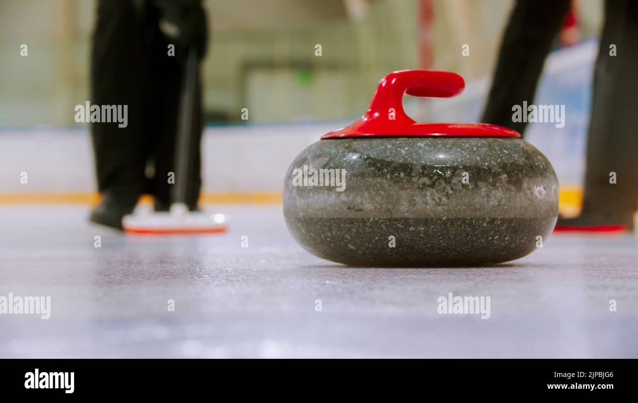 Curling training - a granite stone with red handle on the ice field ...
