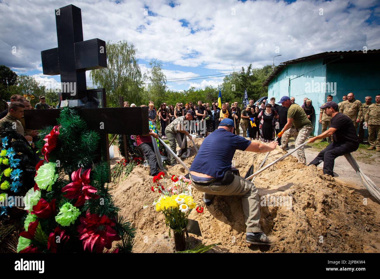 Cemetery workers lower the coffin into the grave during the funeral ...
