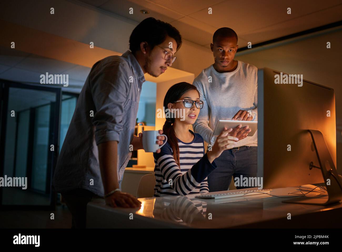 Working together to reach deadlines. computer programmers working together late in the office ...