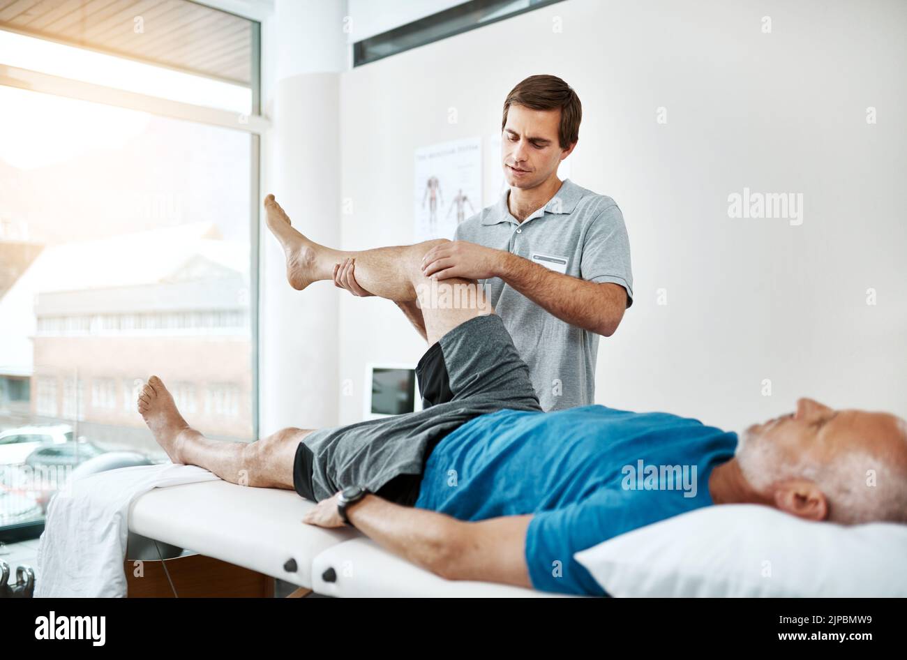 Just relax and keep still. a young male physiotherapist helping a ...