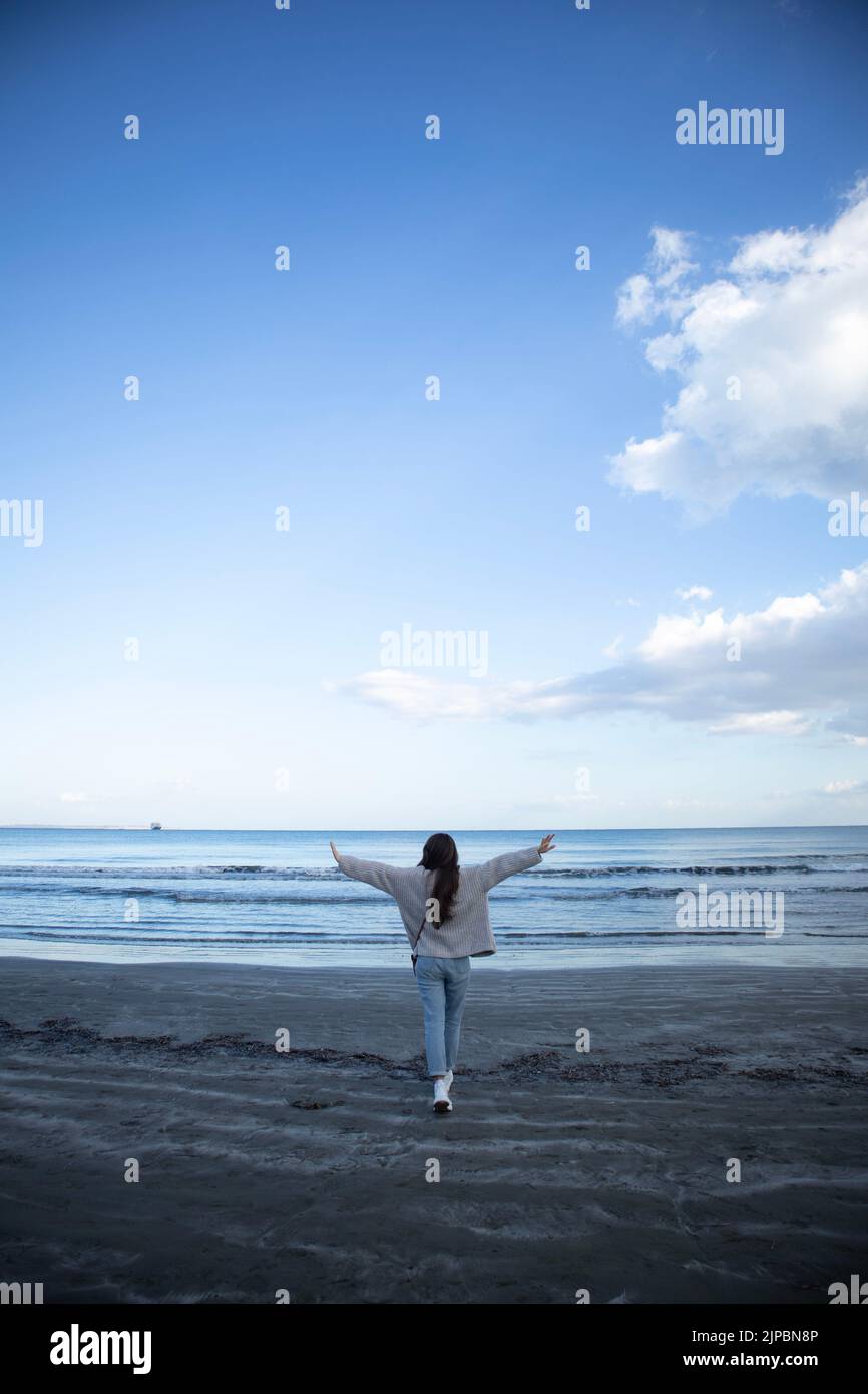 Young woman from behind is running at the beach to the sea in Larnaca ...
