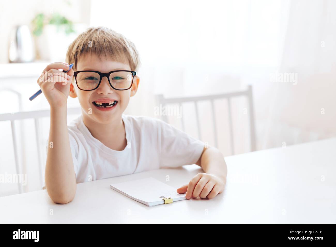 A boy in eyeglasses writes letters in a notebook with a pen Stock Photo ...