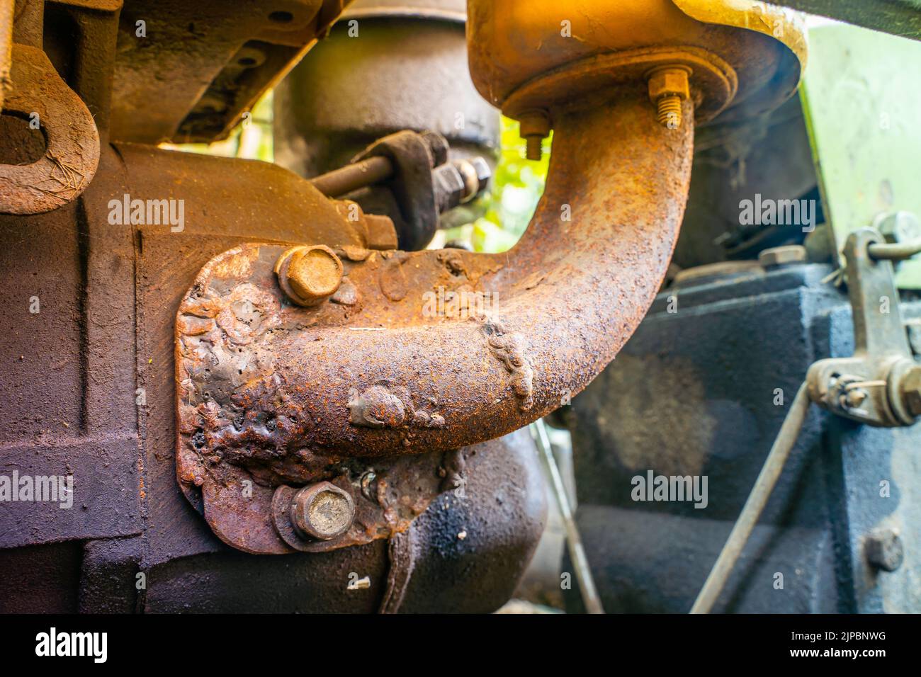 Close-up rusty cooker exhaust pipe of a walk-behind tractor attached to ...