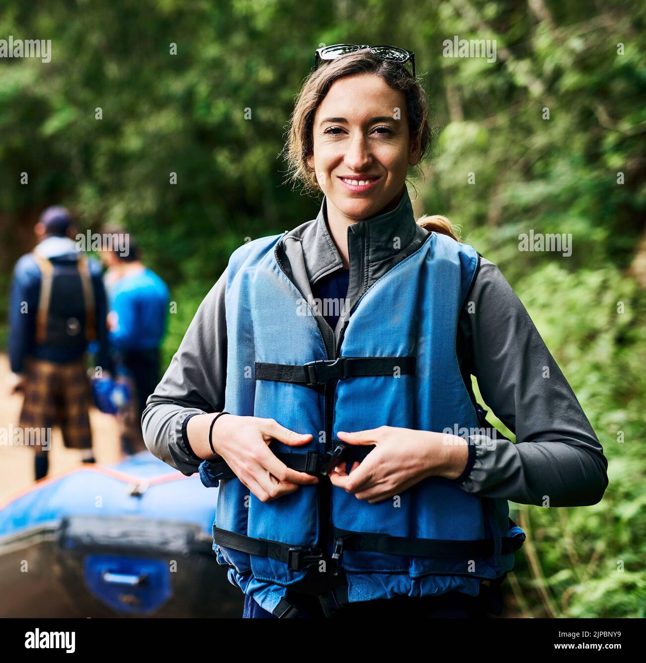 She is ready to go rafting. Portrait of a cheerful young woman putting ...