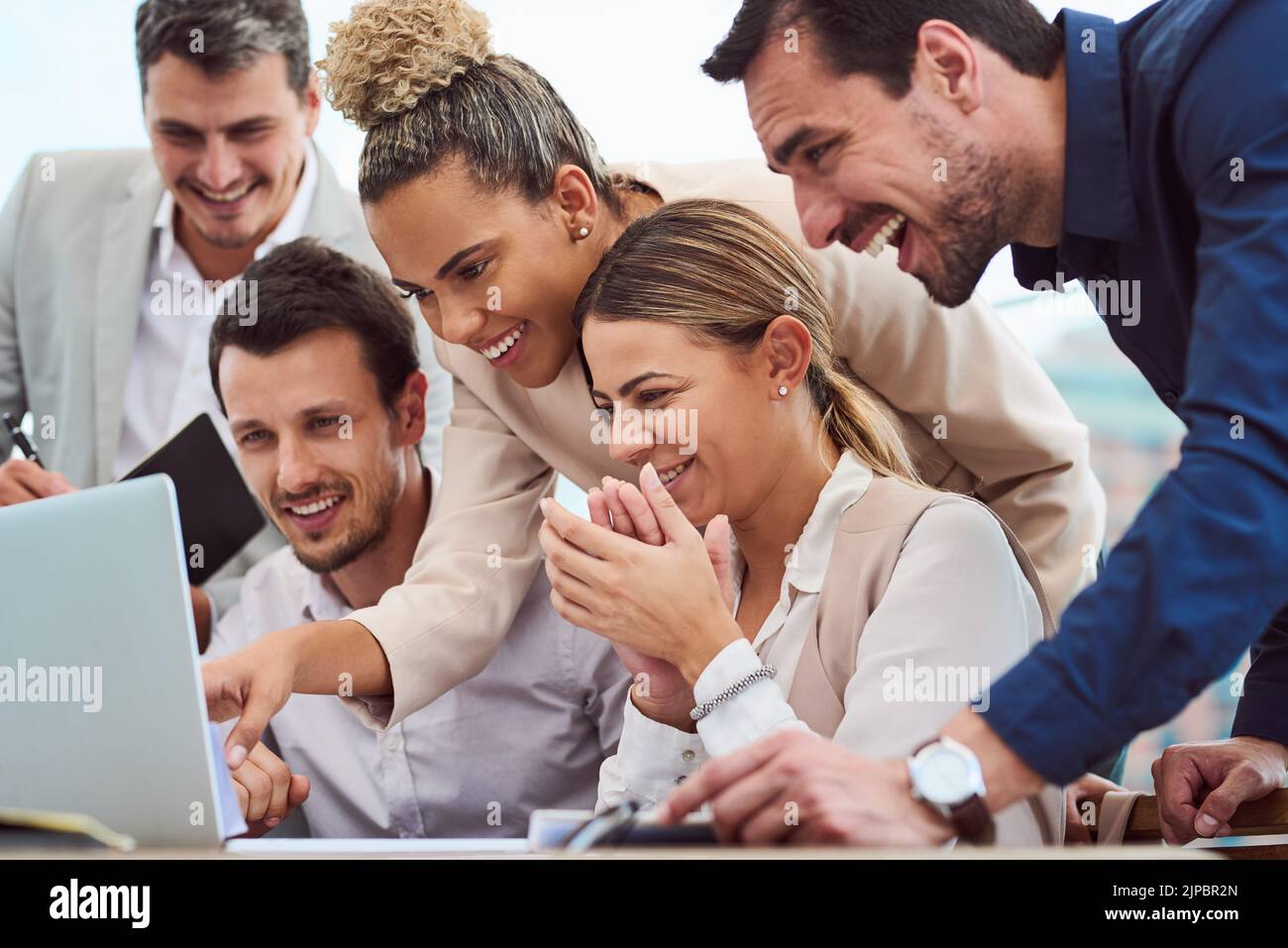 Giving their input. a group of businesspeople gathered around a laptop ...