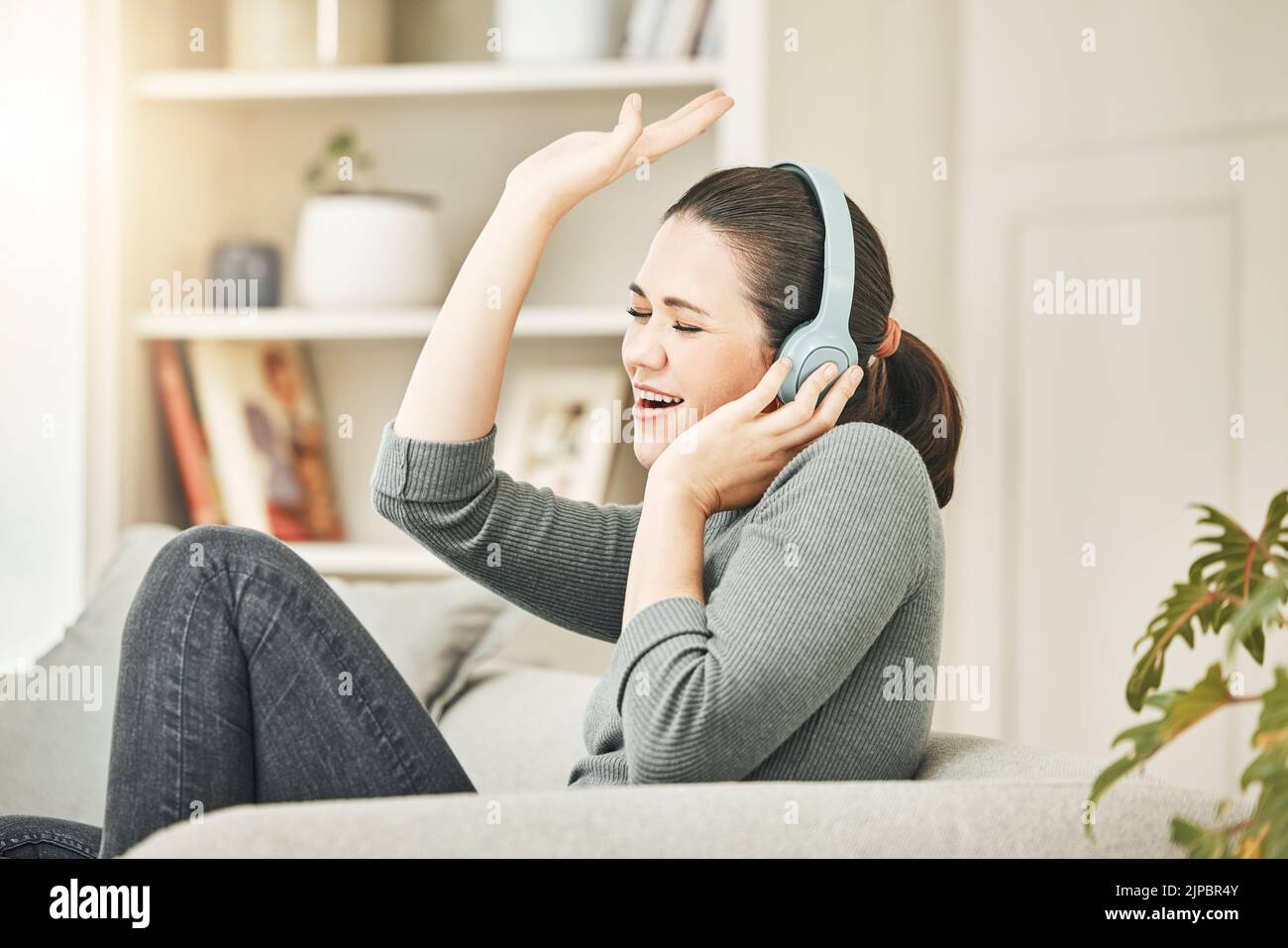 Carefree, smiling and relaxed woman listening to music, singing and ...